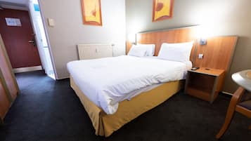 Quarto de hotel com uma cama grande, duas mesas de cabeceira, uma cadeira e obras de arte nas paredes.