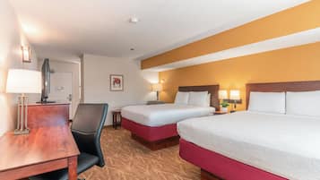 Quarto de hotel com duas camas, uma escrivaninha, uma cadeira e uma televisão.