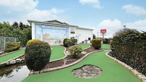 Um campo de minigolfe com um mural, um edifício branco e uma placa para o Ocean Star Inn.