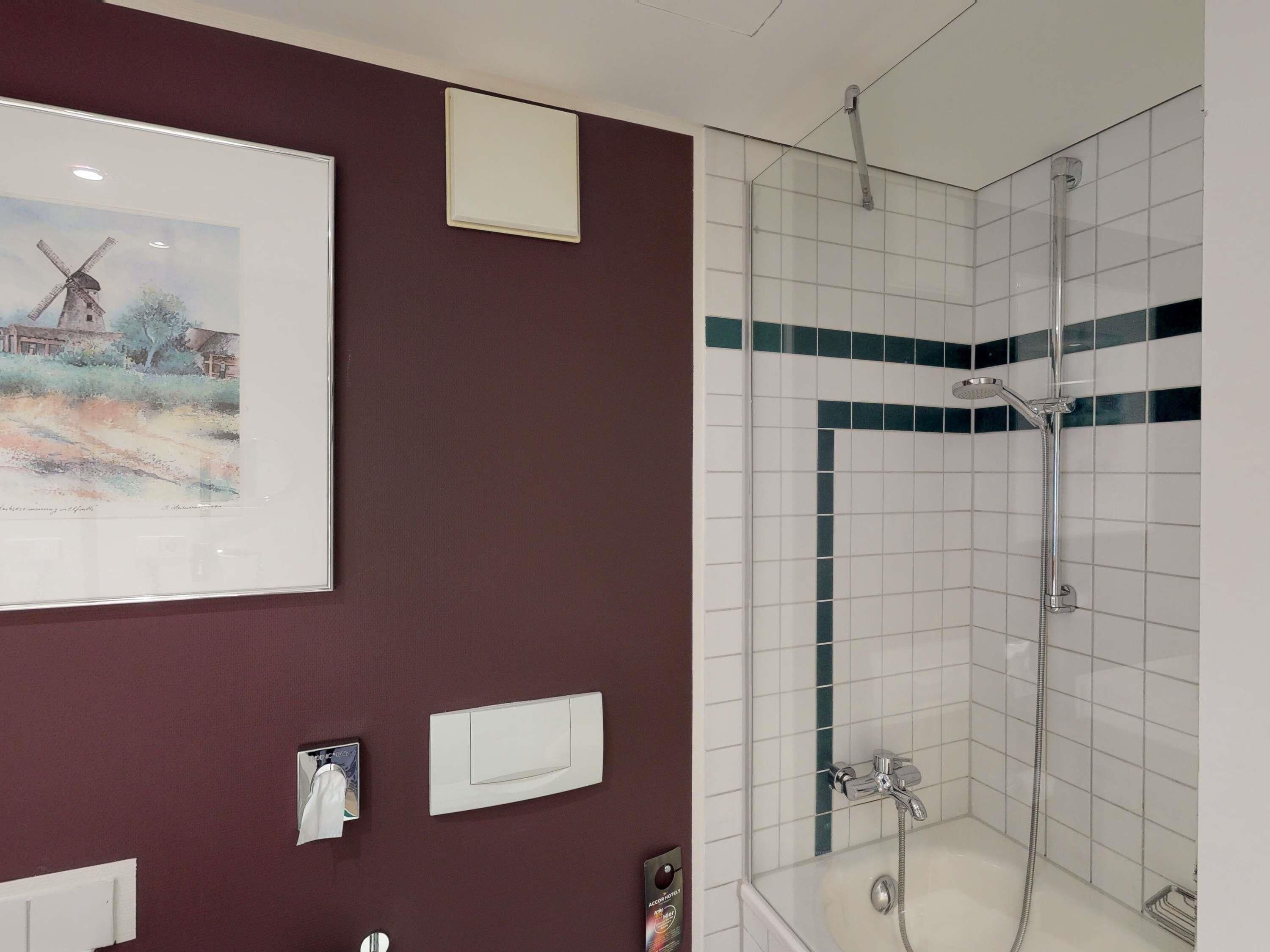 Casa de banho com chuveiro, um quadro emoldurado e um porta-toalhas.