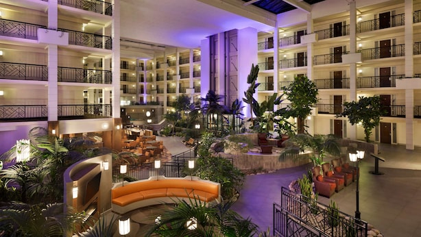 Um átrio de hotel com vários níveis, varandas, áreas de estar e plantas dentro de casa.