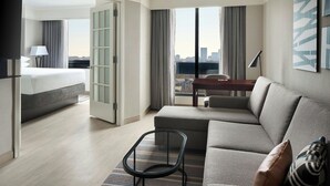 Quarto de hotel com uma cama, um sofá, uma mesa pequena e uma televisão.