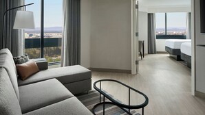 Quarto de hotel moderno com uma grande janela, um sofá, uma mesinha e uma cama.