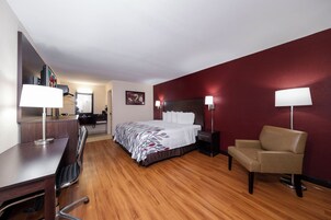 Quarto de hotel com cama, abajures, escrivaninha, cadeira e espelho.