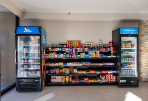 Área de máquinas de venda automática com máquina de sorvetes Blue Bunny e um refrigerador com diversos lanches e bebidas.