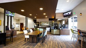 Um restaurante moderno com área de jantar de madeira, um bar e uma cozinha visível ao fundo.