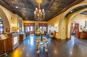 Um hall de entrada com um candelabro, uma recepção e um vaso com flores.