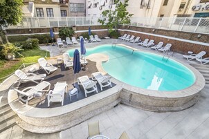 Piscina com espreguiçadeiras e guarda-sóis.
