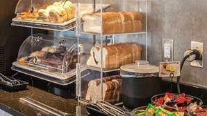 Um buffet com diversos alimentos, incluindo pão e doces, expostos em recipientes transparentes.
