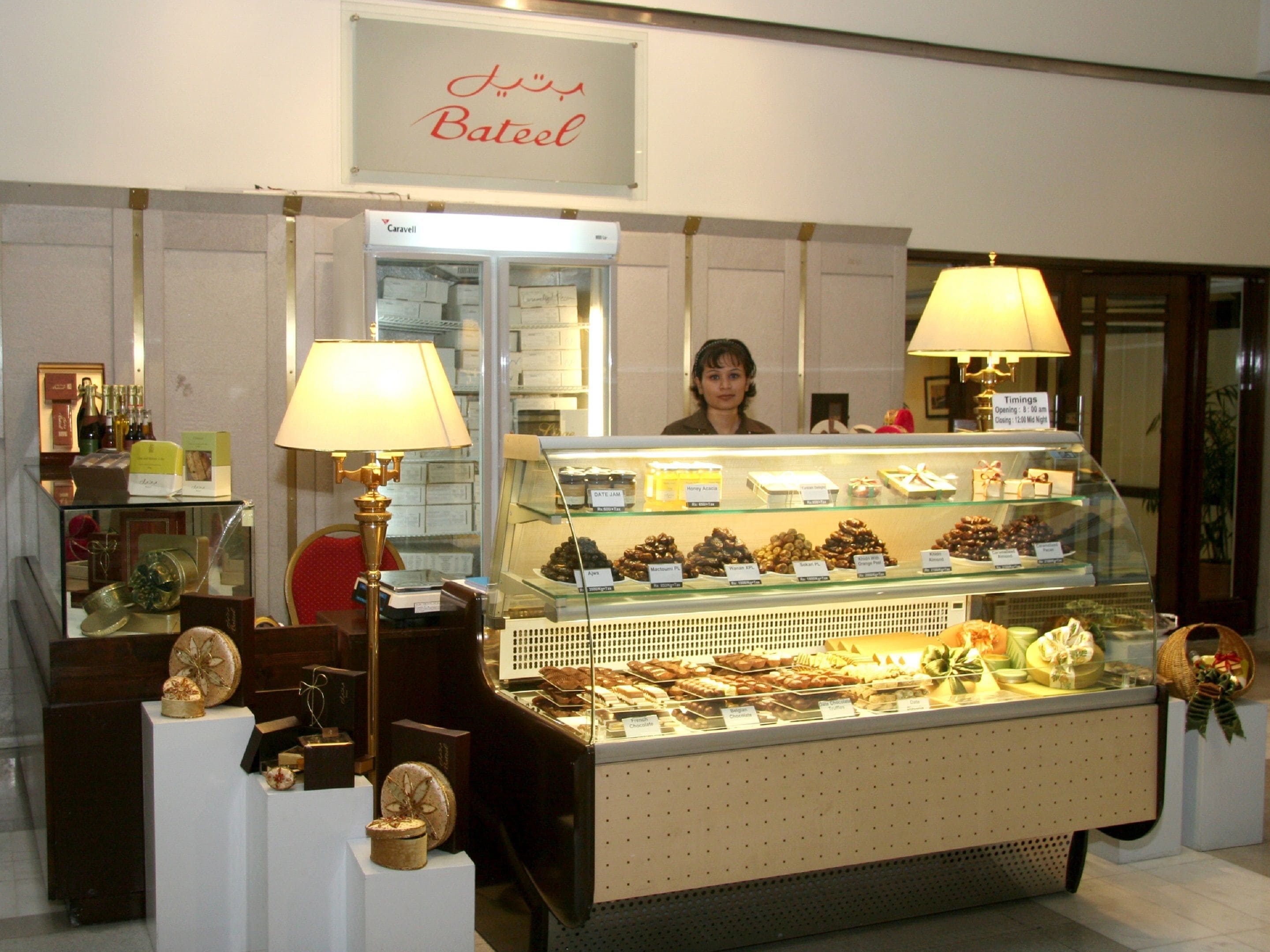 Vitrine de pastelaria com diversos produtos de panificação e um letreiro com a inscrição 'Bateel'.