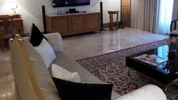 Uma sala de estar com sofá, mesa de centro, televisão e tapete estampado.