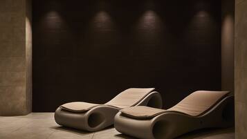 Uma área de relaxamento moderna com duas poltronas e uma parede escura.