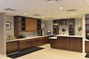 Uma cozinha moderna com armários de madeira, uma ilha central e um espaço bar com garrafas de bebidas.
