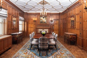 Uma sala de jantar formal com uma grande mesa de madeira, cadeiras combinando e um lustre.