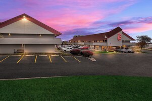 Um Red Roof Inn com estacionamento e área gramada na frente.