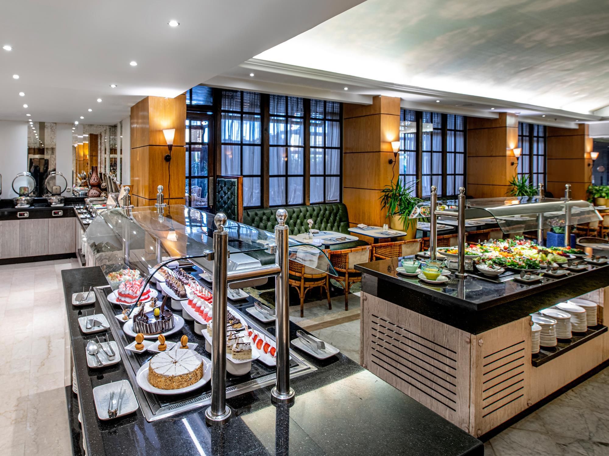 Disposição de buffet com diversos alimentos e área de estar com um sofá estofado verde.