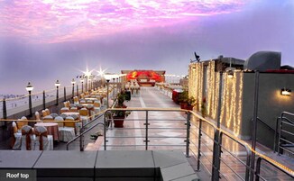Terraço no telhado com mesas, cadeiras, guarda-corpo e vista para o horizonte da cidade.