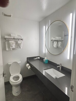 Casa de banho moderna com sanita, lavatório e porta-toalhas.