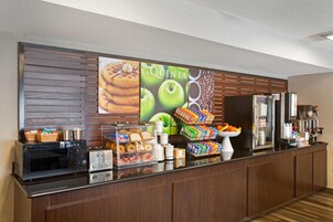 Bancada de café da manhã com diversos alimentos e um grande cartaz anunciando 'La Quinta'.
