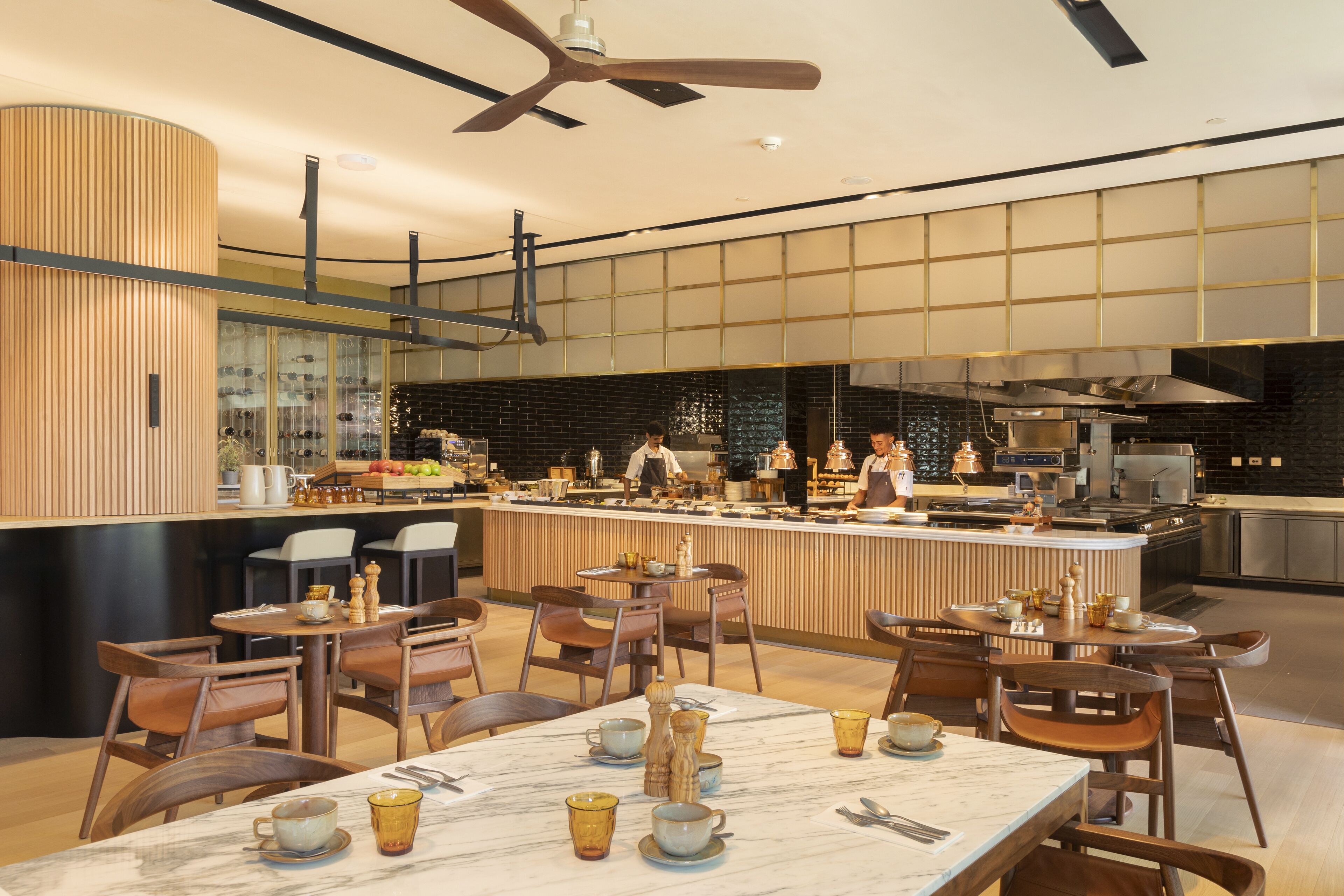 Um restaurante moderno com área de bar, cadeiras de madeira e uma mesa de mármore.