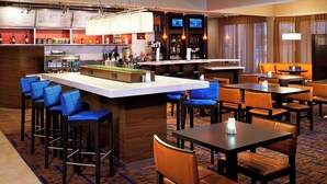 Uma área de bar em hotel, com balcão, assentos e televisões.