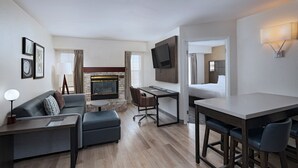 Quarto de hotel moderno com lareira, sofá, escrivaninha e televisão.