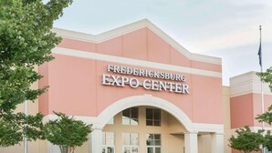Fachada do Frederickburg Expo Center com um letreiro grande, entrada em arco e vegetação ao redor.