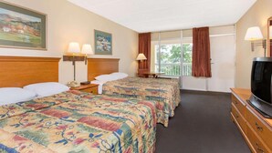 Quarto de hotel com duas camas, televisão, escrivaninha e janela com cortinas.