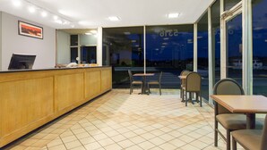 Um restaurante com balcão de madeira, chão de azulejos e paredes de vidro.