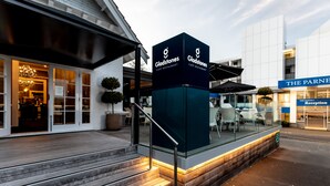 Um café-restaurante moderno com entrada convidativa, mesas ao ar livre e área de recepção.