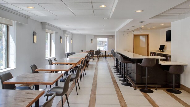 Uma área de refeições moderna com mesas longas, cadeiras e um bar.