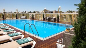 Piscina no terraço com espreguiçadeiras e deck de madeira.