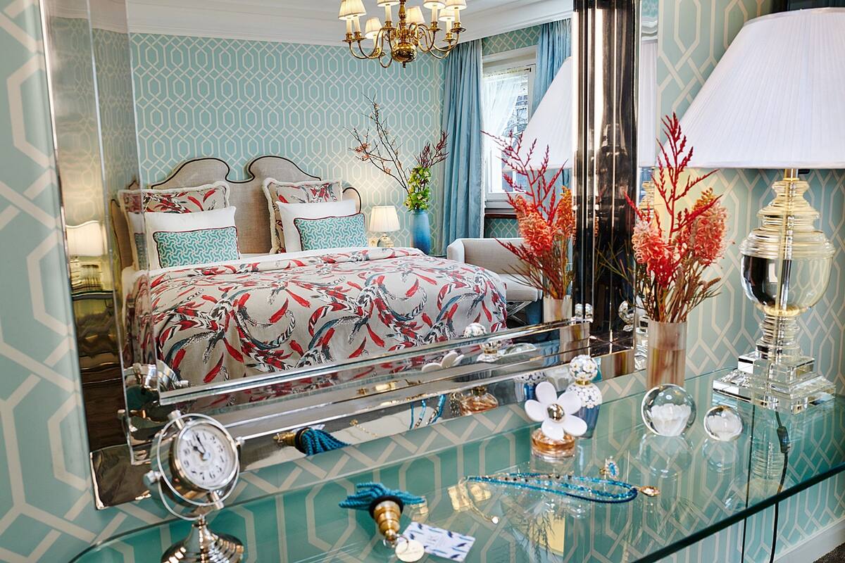 Quarto com cama, penteadeira, espelho e lustre.