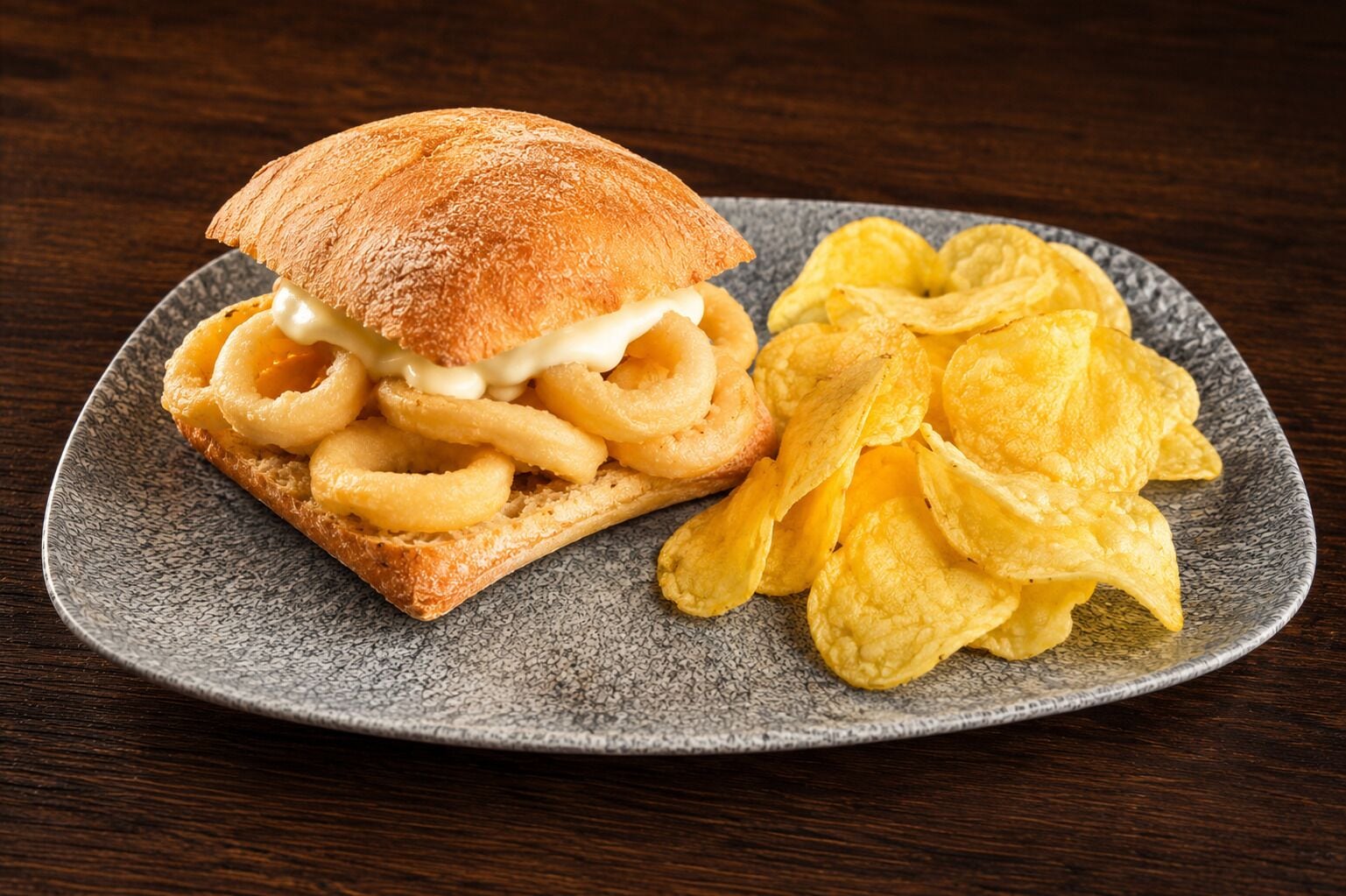 Um sanduíche com anéis de cebola e batatas fritas num prato.