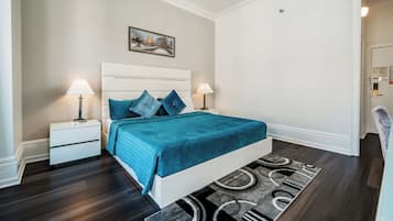 Quarto com cama, mesas de cabeceira, um quadro e um tapete estampado.