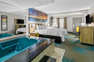 Quarto de hotel com uma cama grande, banheira, escrivaninha e televisão.