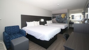 Quarto de hotel com duas camas, uma escrivaninha, uma cadeira e um sofá pequeno.