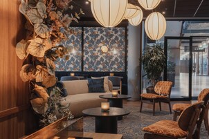 Um hall com sofá, cadeiras, mesa de centro e parede com padrão decorativo.