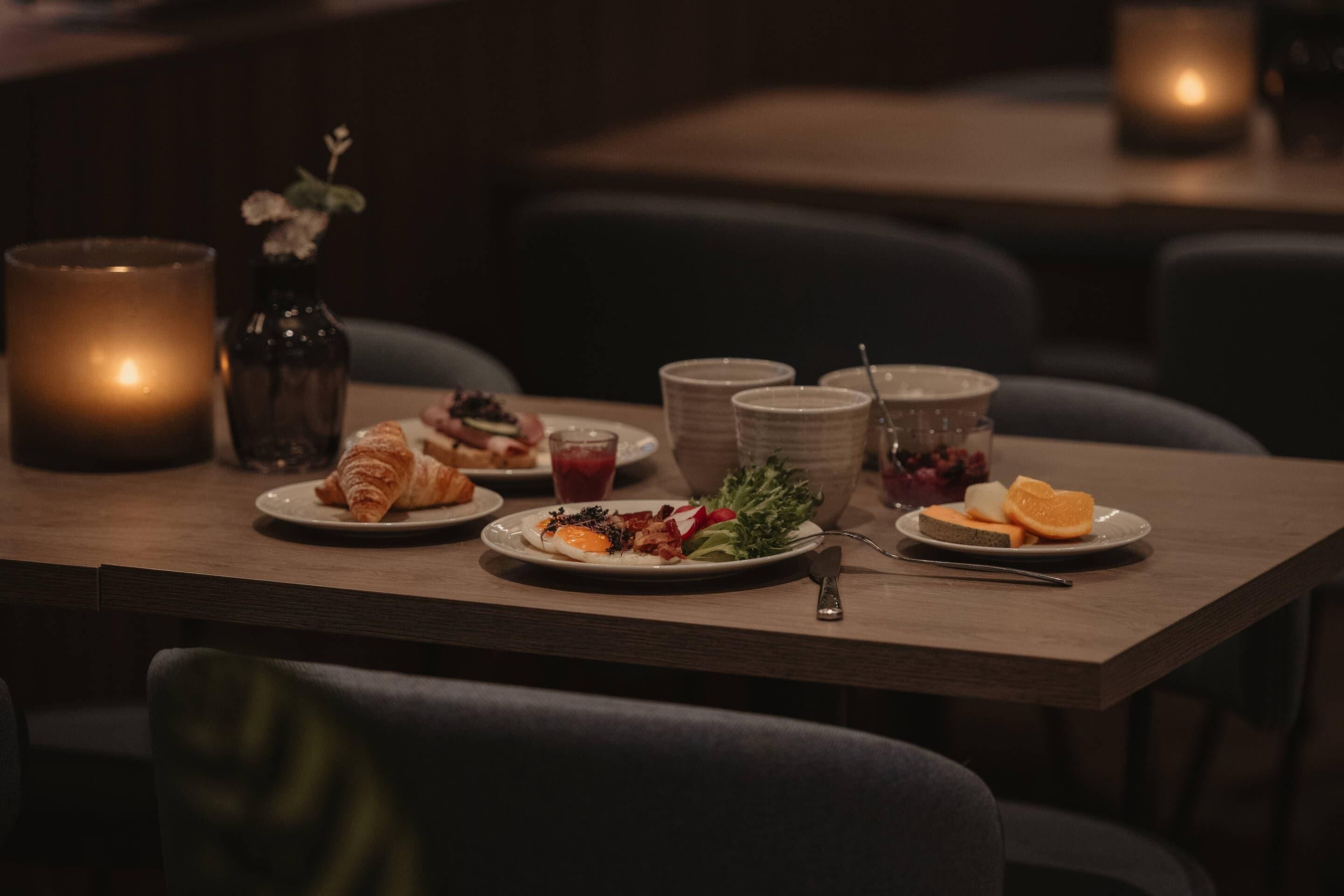 Uma mesa de jantar com pratos de comida, uma vela e um vaso com flores.