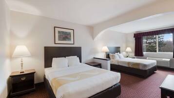Quarto de hotel com duas camas, uma mesa de trabalho e uma janela com cortinas.