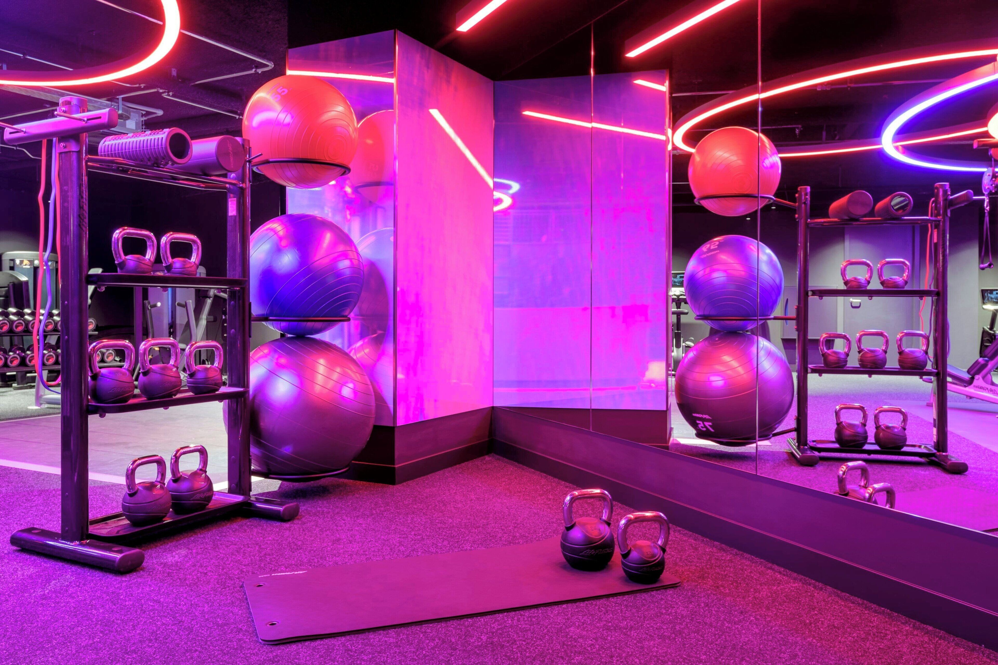 Uma academia com equipamentos de ginástica, iluminação neon e um espelho grande.