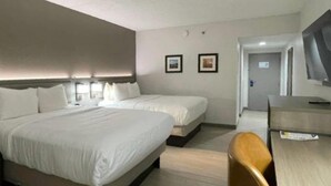 Quarto de hotel com duas camas, uma escrivaninha e uma televisão.