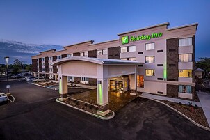 Um hotel Holiday Inn com design moderno, apresentando uma entrada destacada e um estacionamento.