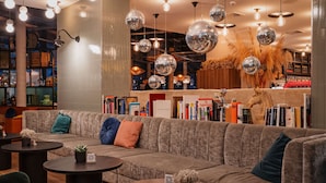 Uma área de estar moderna com sofá, mesas redondas e espelhos decorativos.