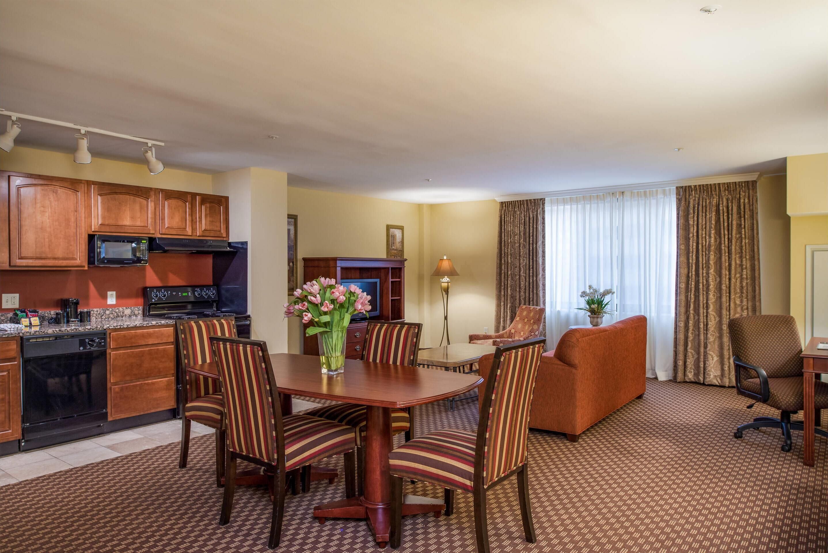 Quarto de hotel com área de refeições, cozinha e espaço de estar.