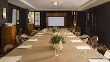 Uma sala de conferência com uma mesa comprida, cadeiras e uma tela de projetor exibindo "LYLE".