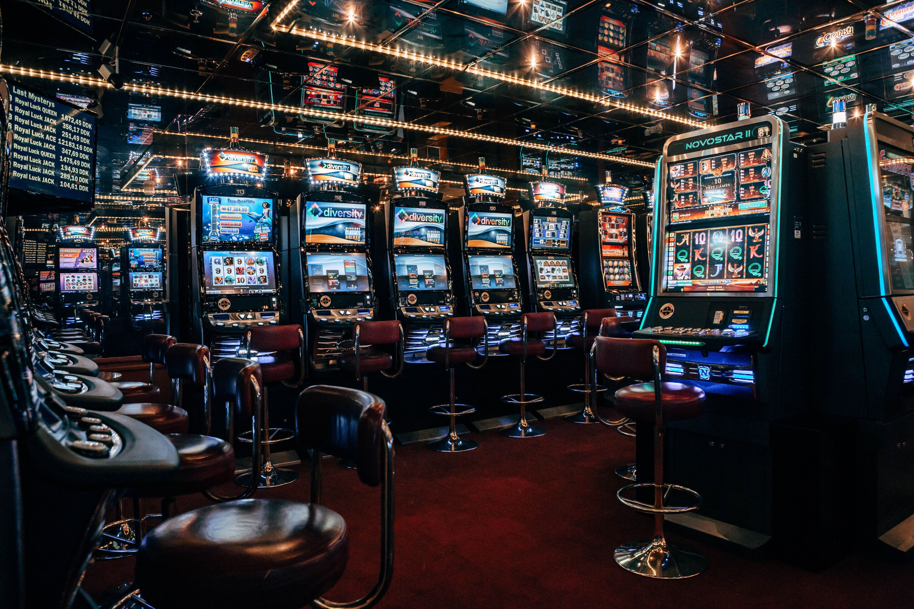 Um cassino com várias máquinas de jogo e banquetas de bar.