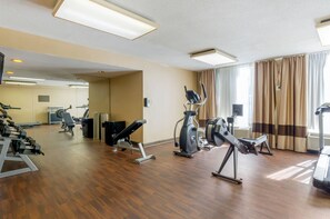 Academia de hotel com equipamentos de cardio, pesos livres e espelho.