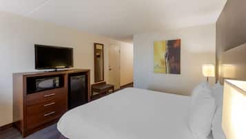 Quarto de hotel com cama, televisão, micro-ondas, escrivaninha e um quadro na parede.