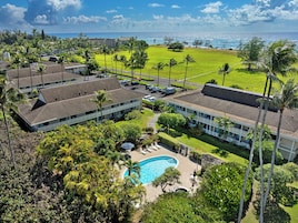 Um hotel com vários edifícios, piscina e vista para o mar.